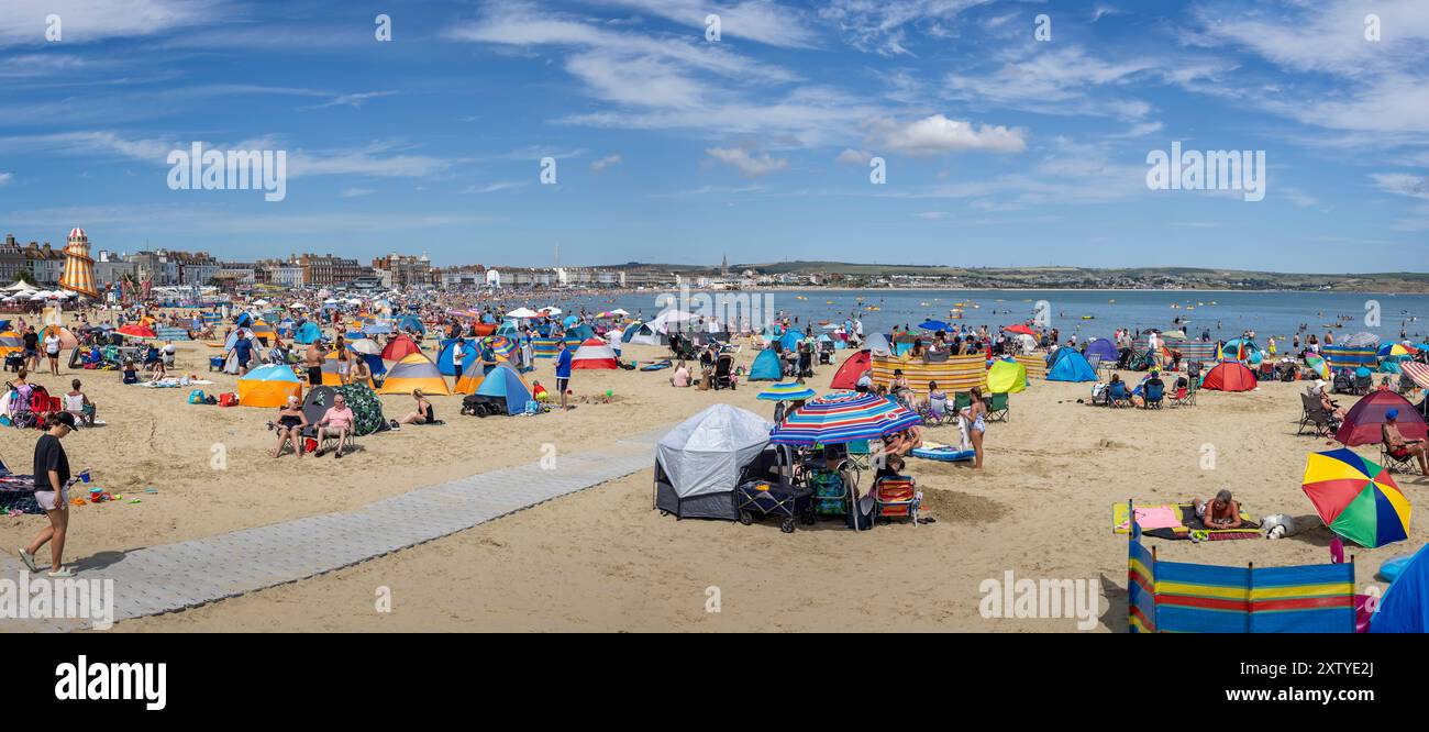 Panorama of crowded beach on a hot summers day in Weymouth, Dorset, UK ...