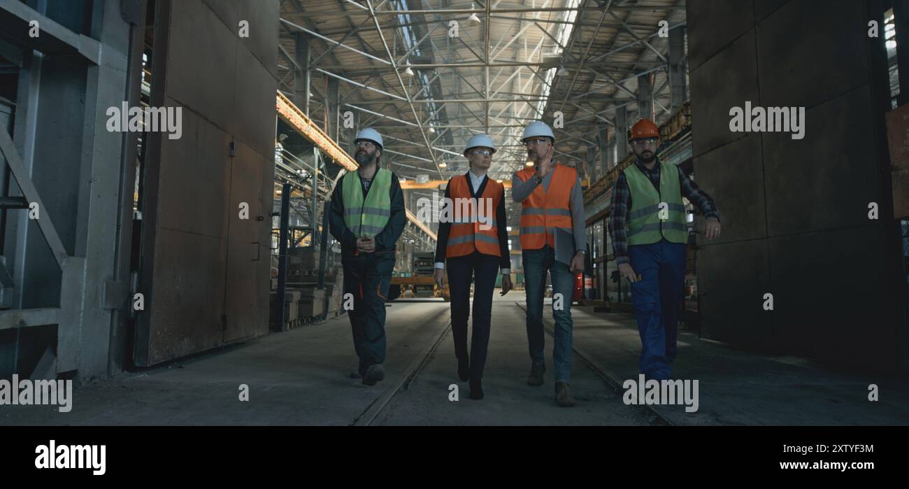 Four heavy industry engineers in safety uniform and hard hats discuss ...
