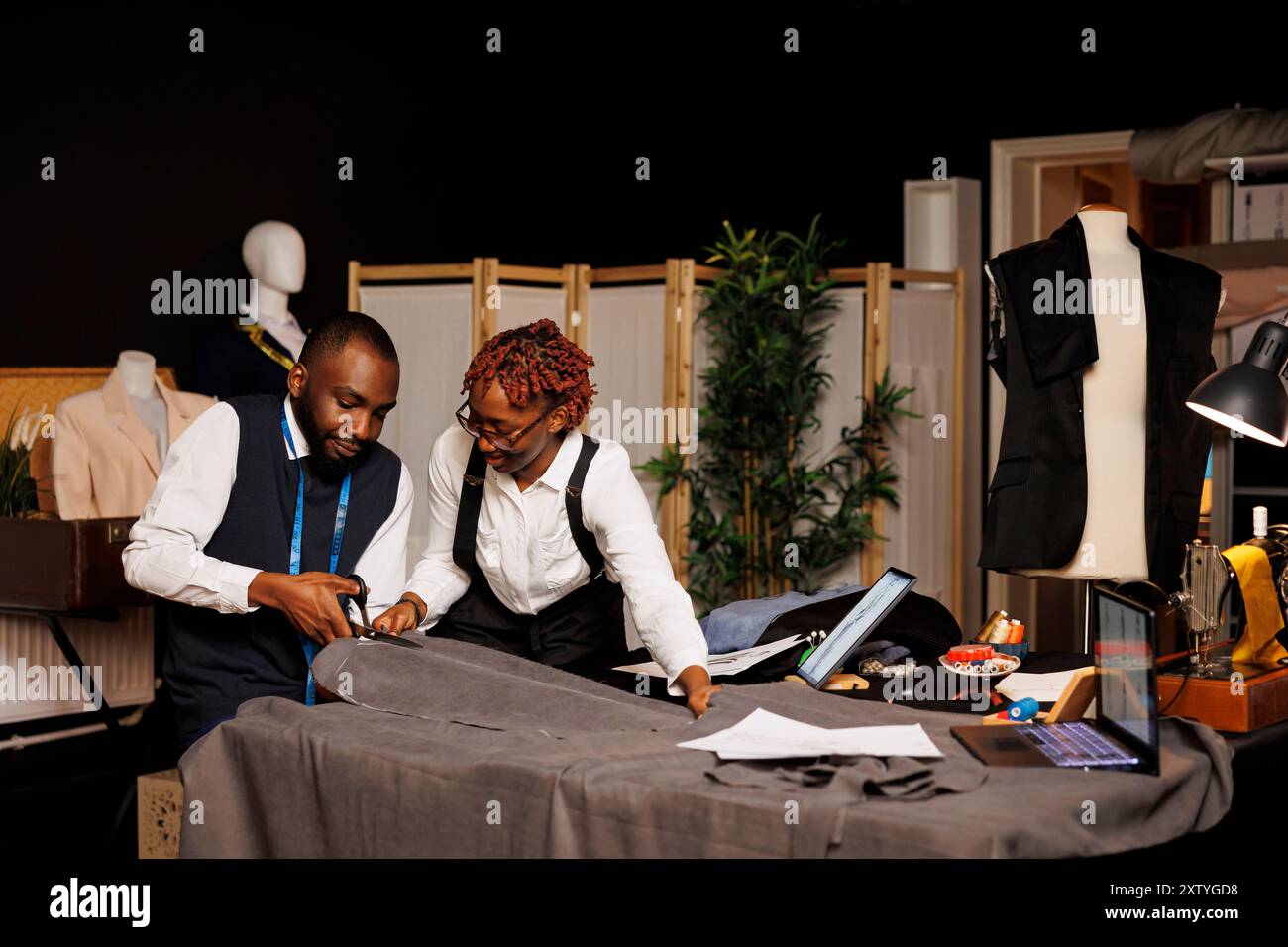 Bespoke tailor coworkers cutting cloth material for fashion collection ...
