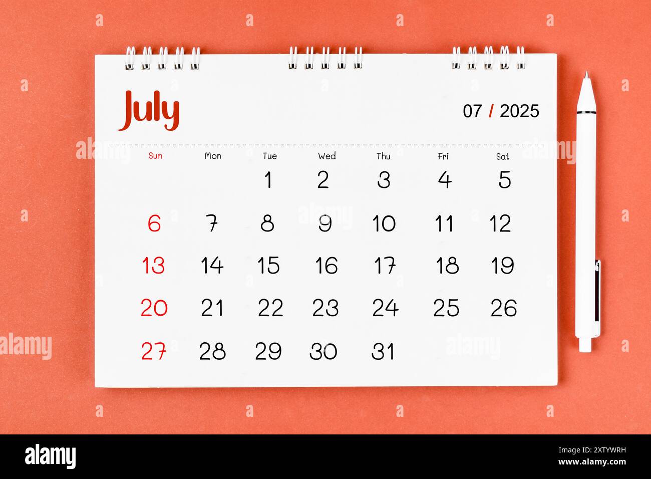 July 2025 Monthly desk calendar for 2025 year and pen on red background ...