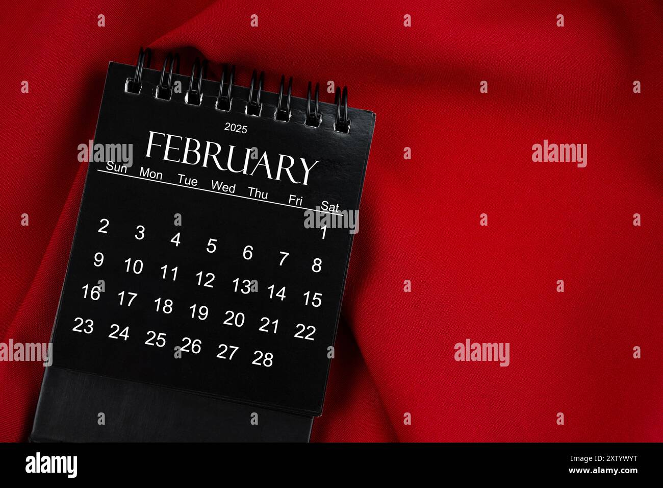February 2025 Black spiral desktop calendar on red textile Stock Photo ...