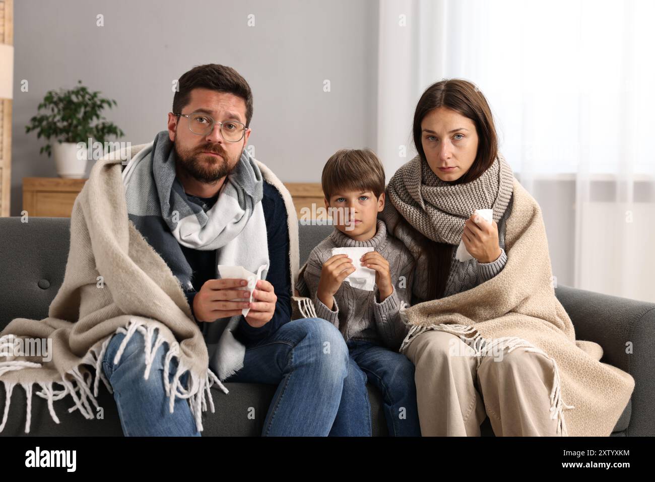 Cold symptom. Family suffering from fever on sofa at home Stock Photo ...