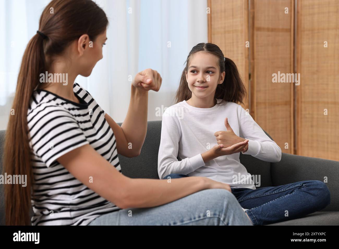 Woman and her daughter using sign language for communication at home ...