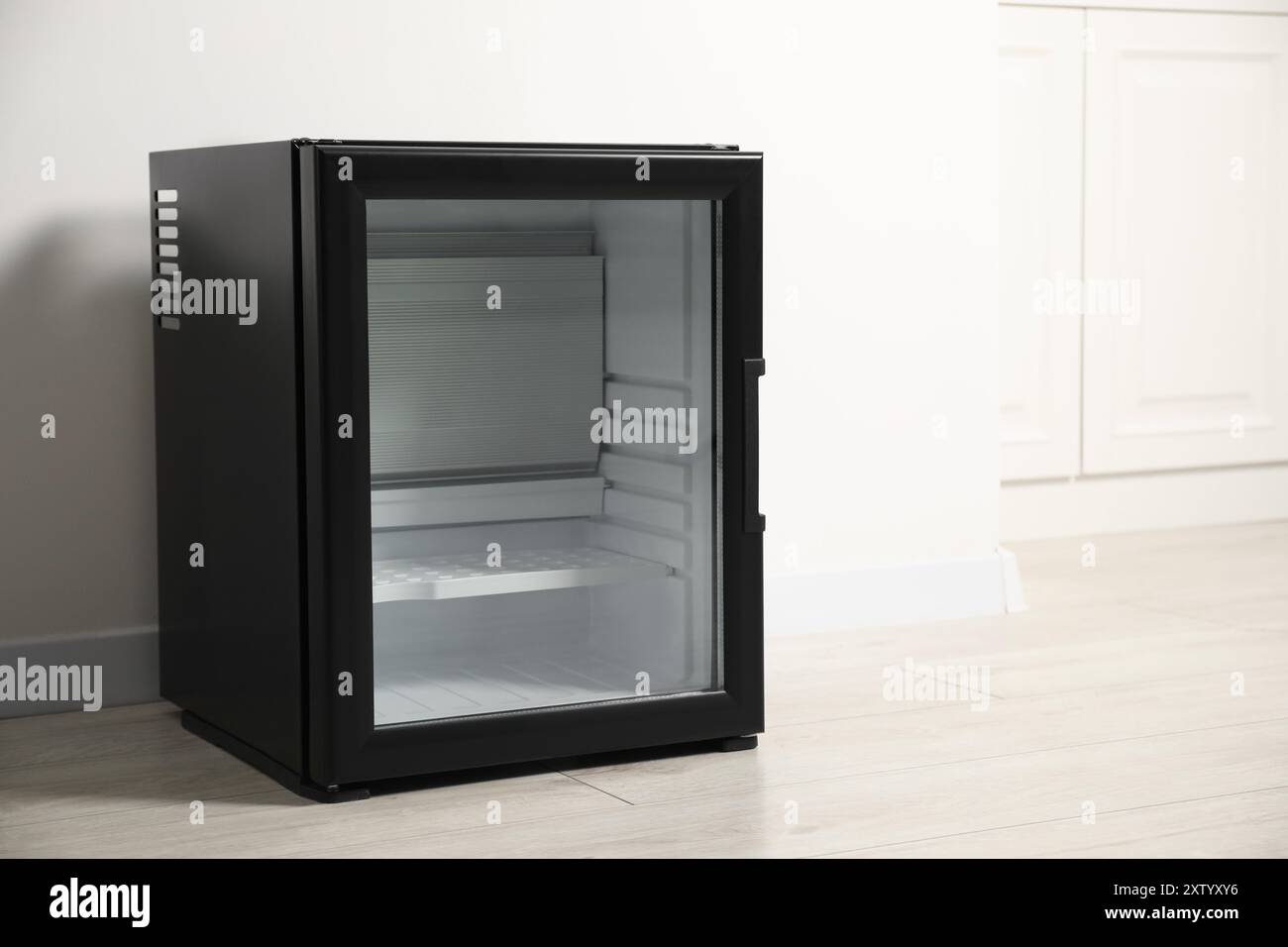 Empty modern mini refrigerator near white wall Stock Photo - Alamy