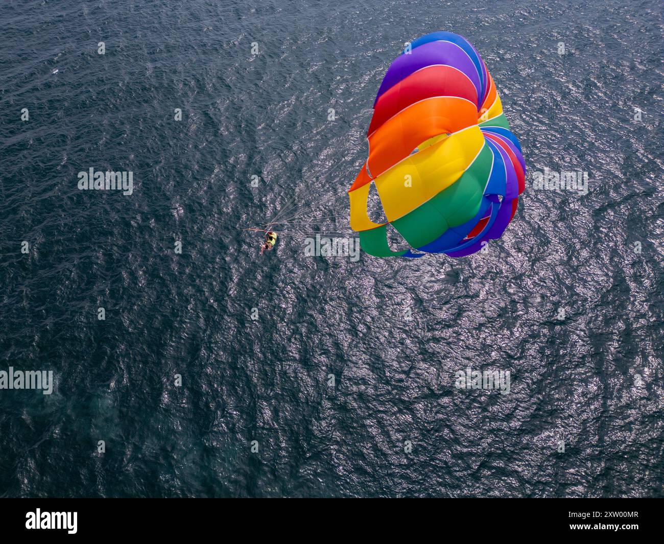 Drone video of a colorful parasail soaring over the open ocean, towed ...