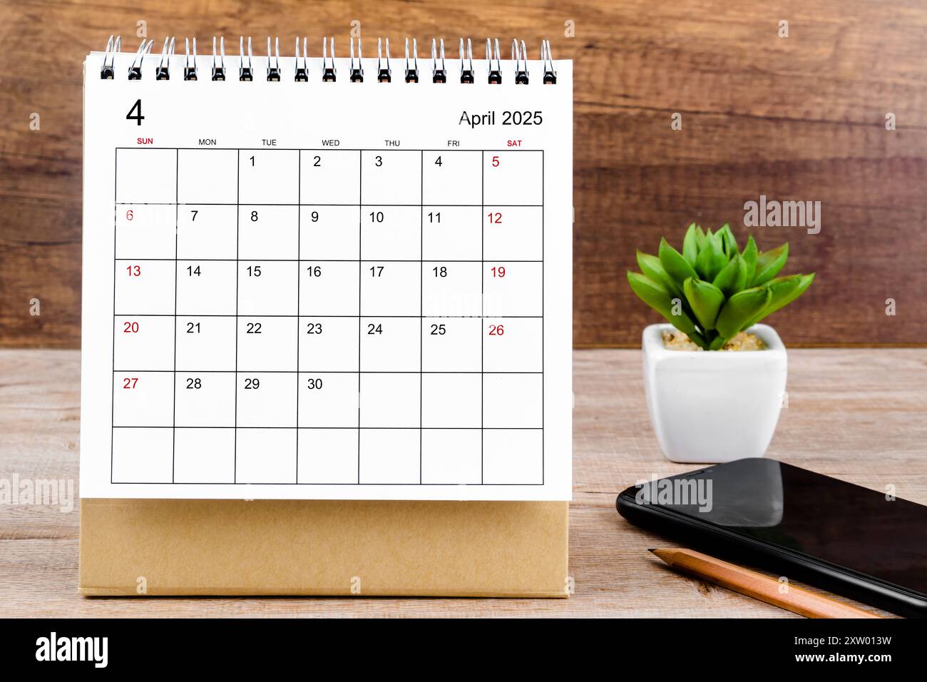 A April 2025 desk calendar on wooden table with black smartphone Stock ...