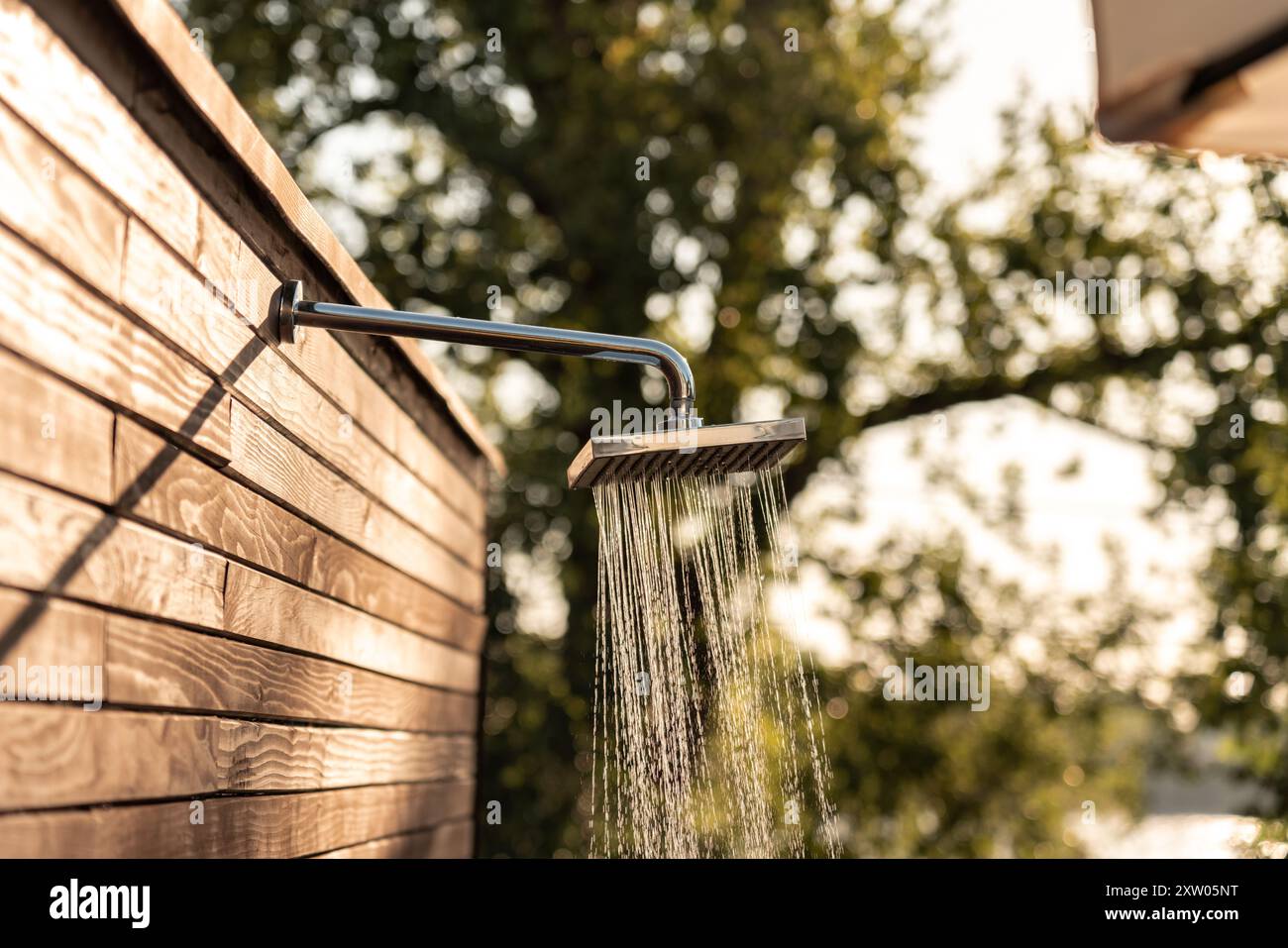 Flowing water from outdoor shower at sunset near pool. Concept of ...