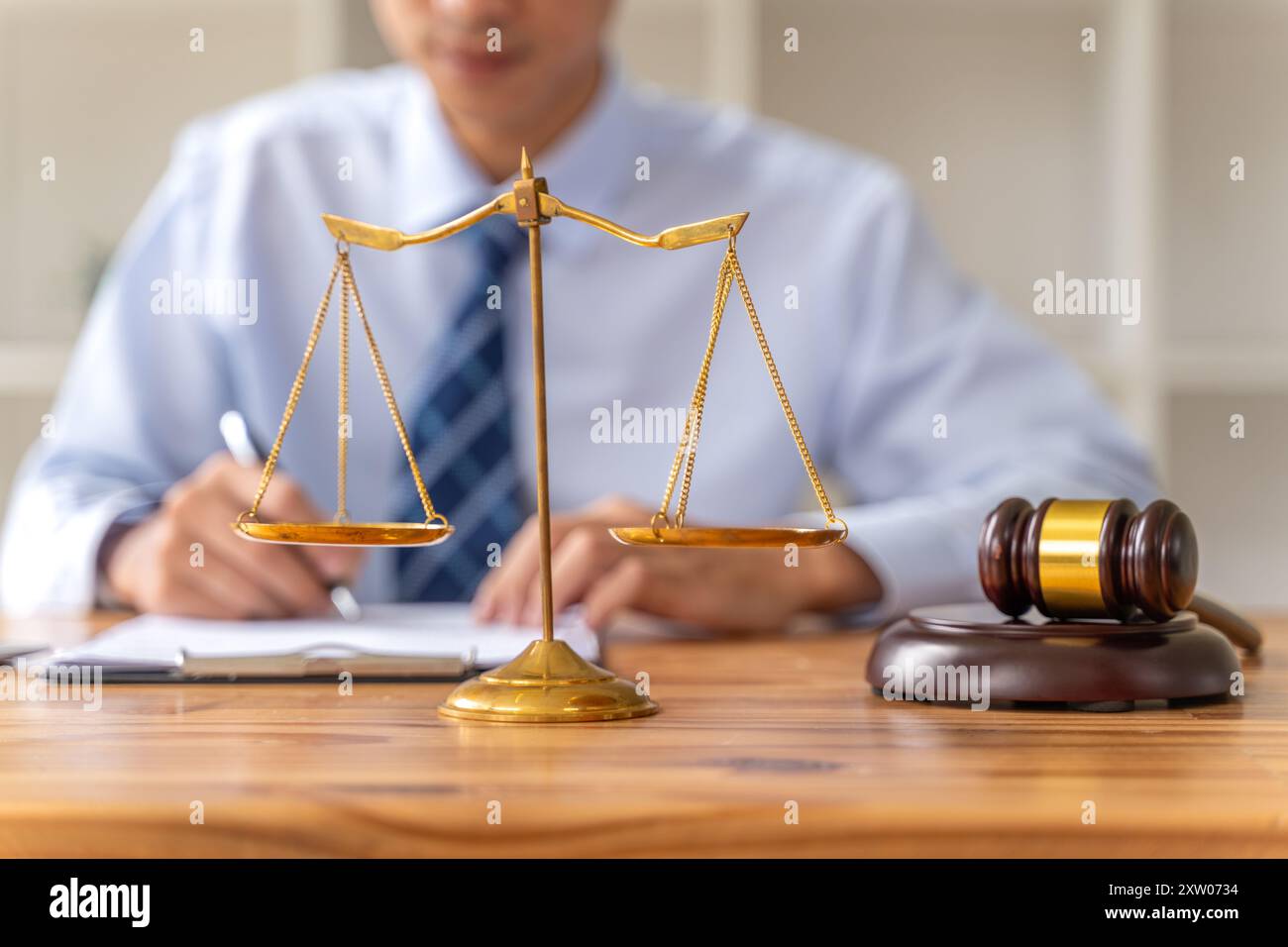 Close up of justice scale and court gavel with blurred working male ...