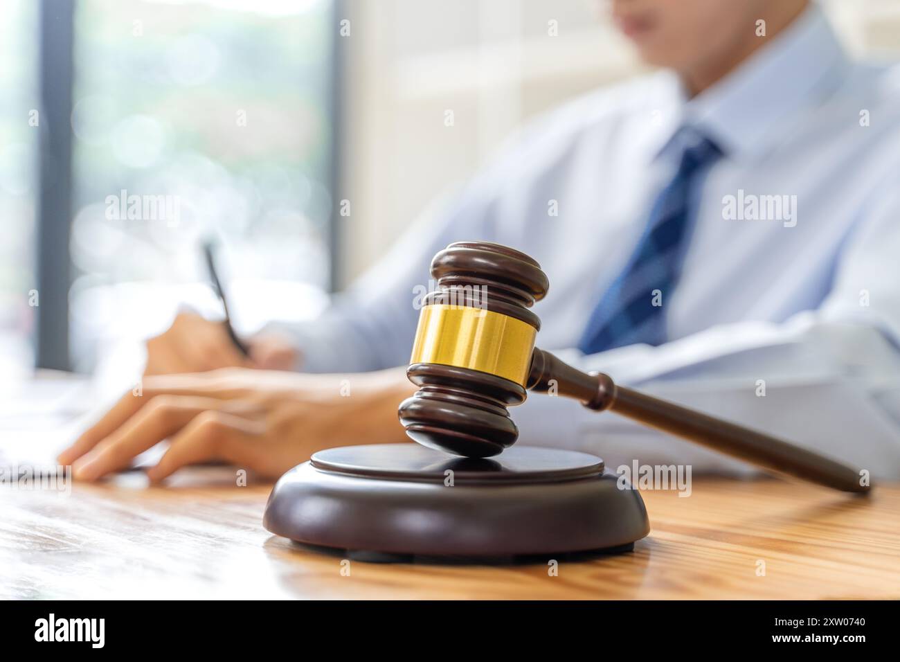 Close up of court gavel with blurred working male lawyer in background ...