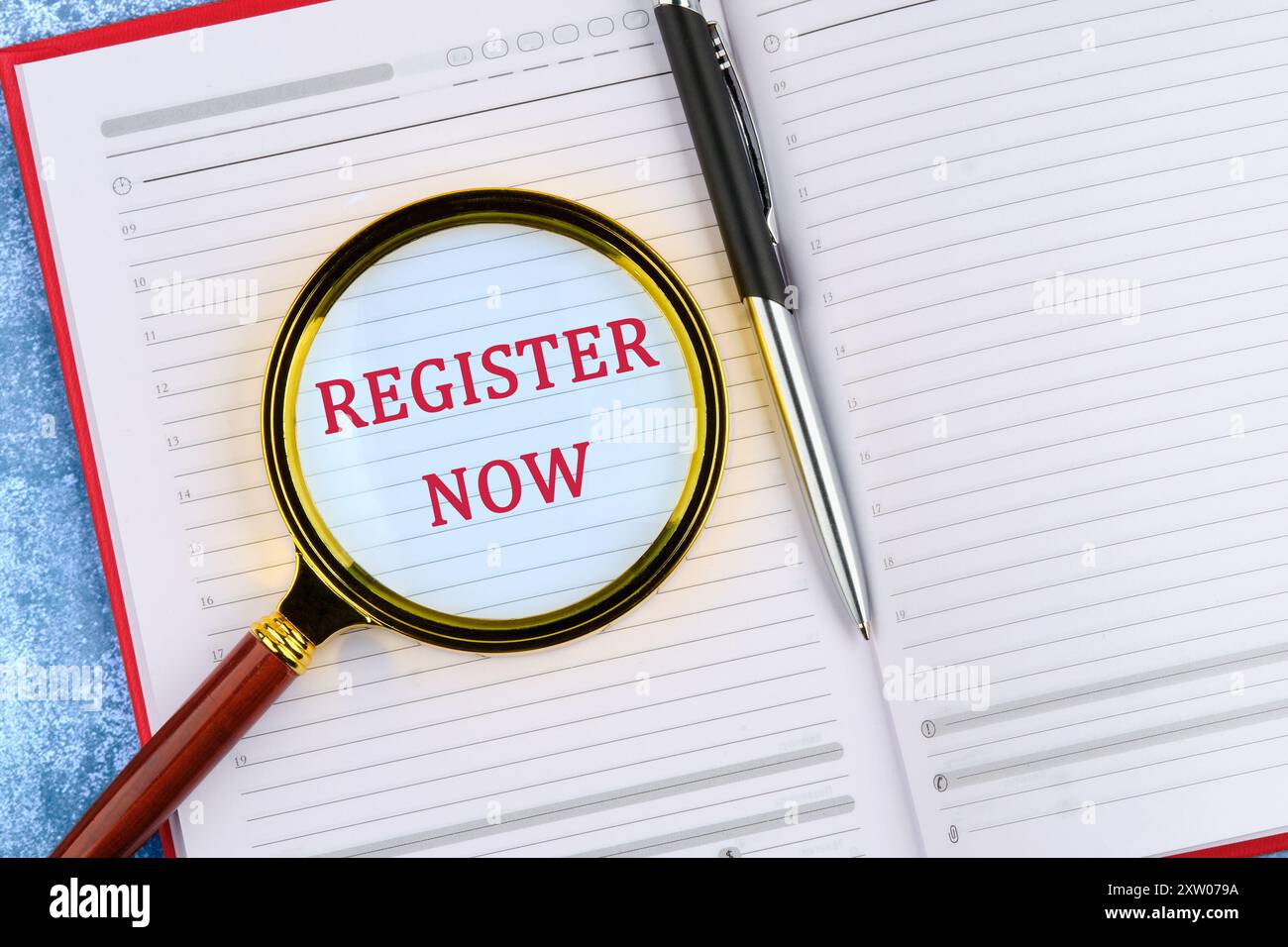 REGISTER NOW words written through a magnifying glass in an open ...