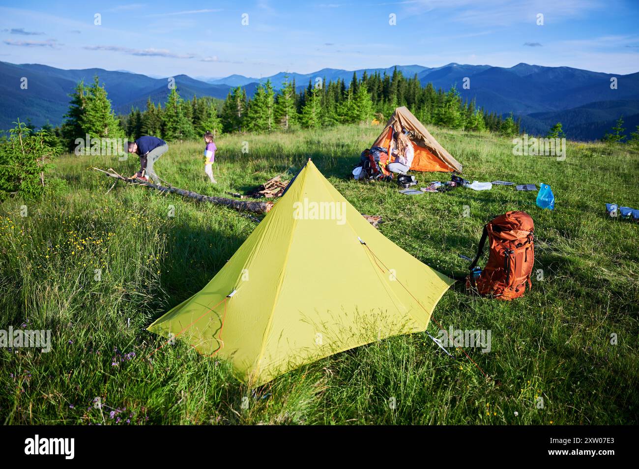 Picturesque mountain campsite on grassy hill with tents. Camper and ...