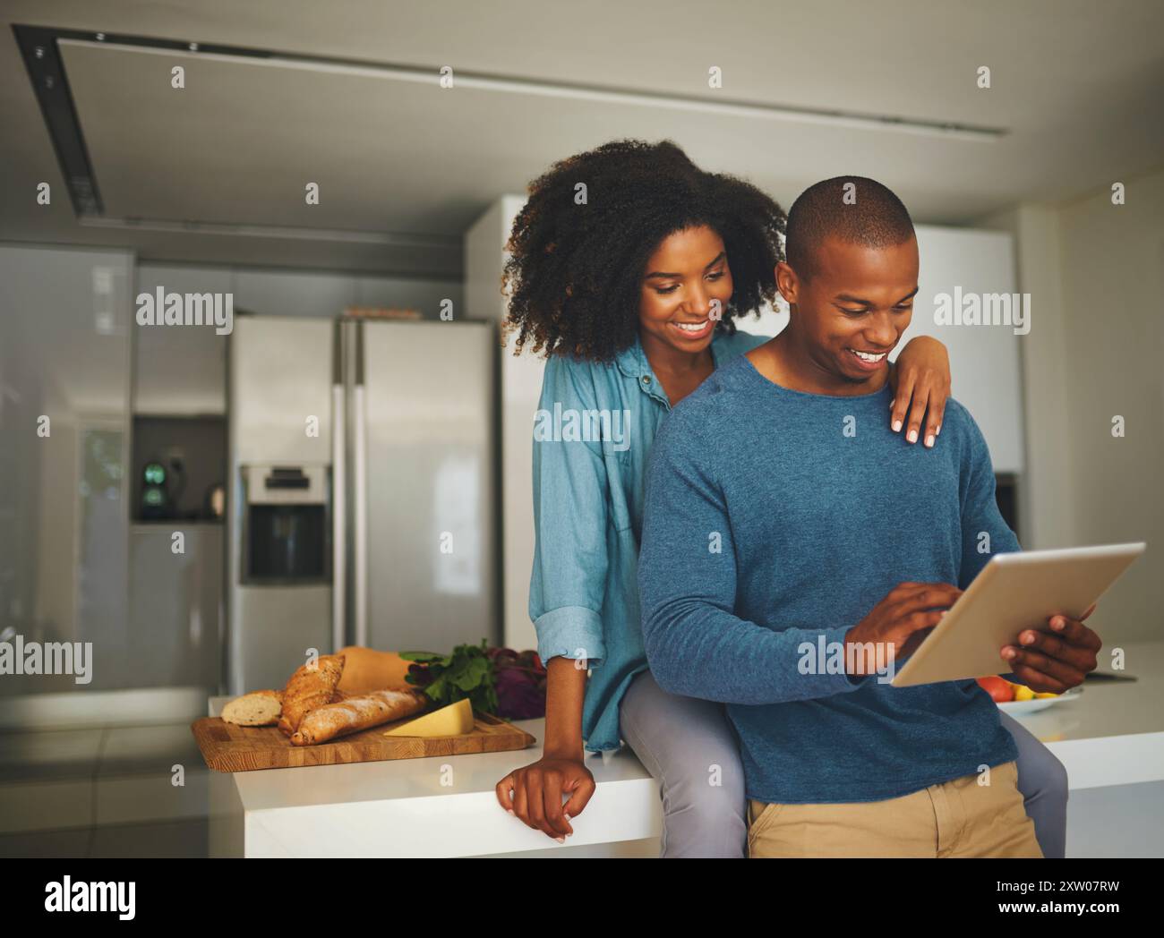 Black couple, happy and tablet in kitchen with love, hug and reading ...