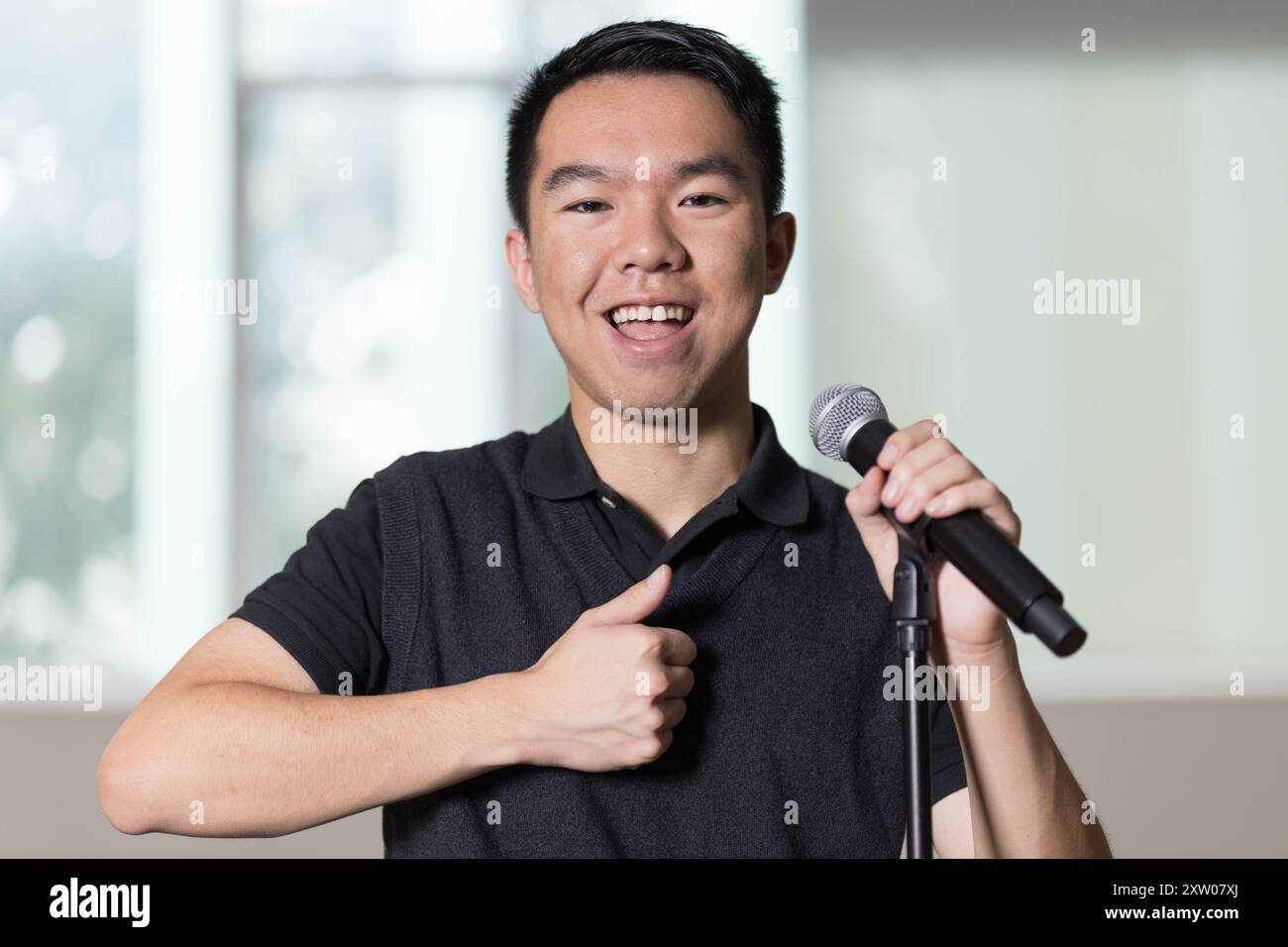 A young teenage male college student is giving a thumbs up while ...