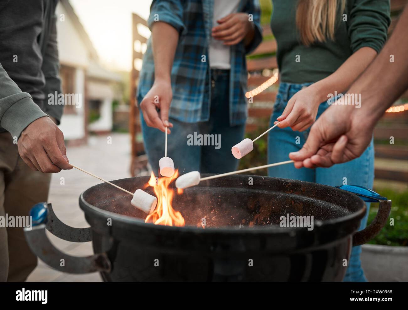 Flame, hands and people roasting marshmallows in backyard for social ...