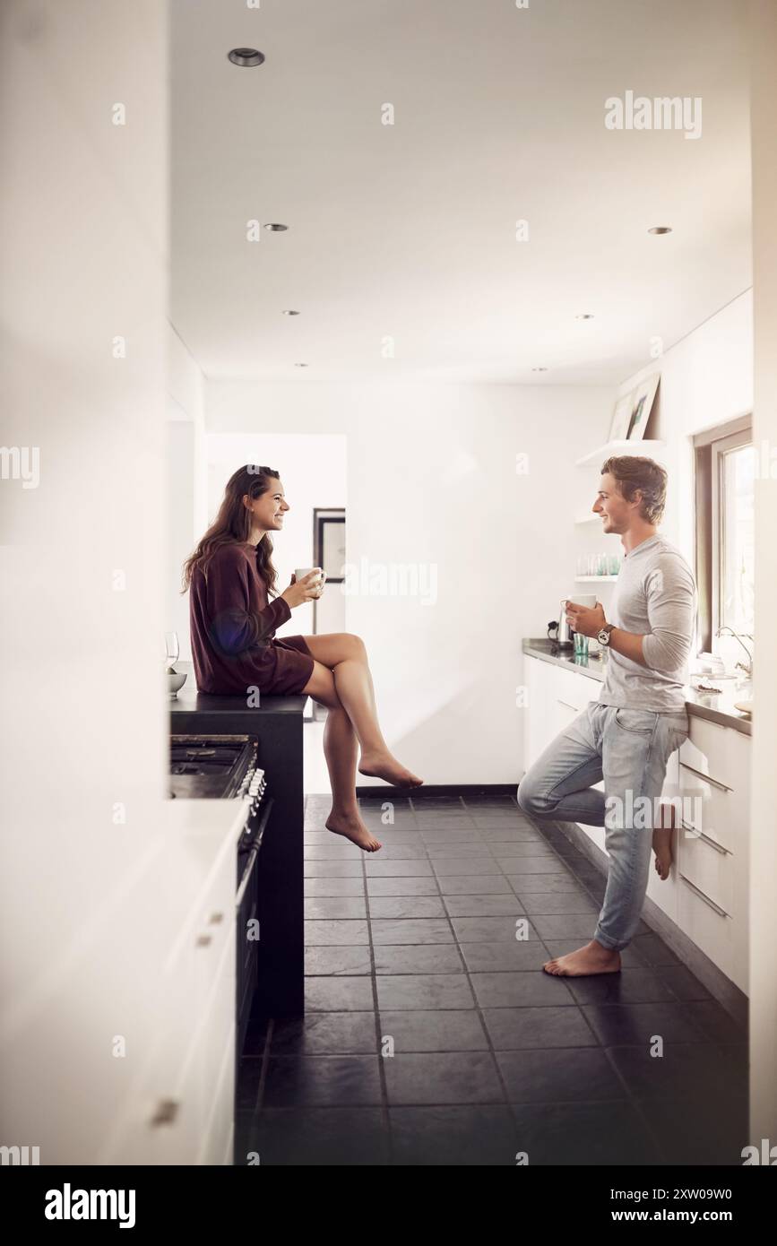 Talk, love and couple in kitchen with coffee, morning discussion and bonding together in home ...