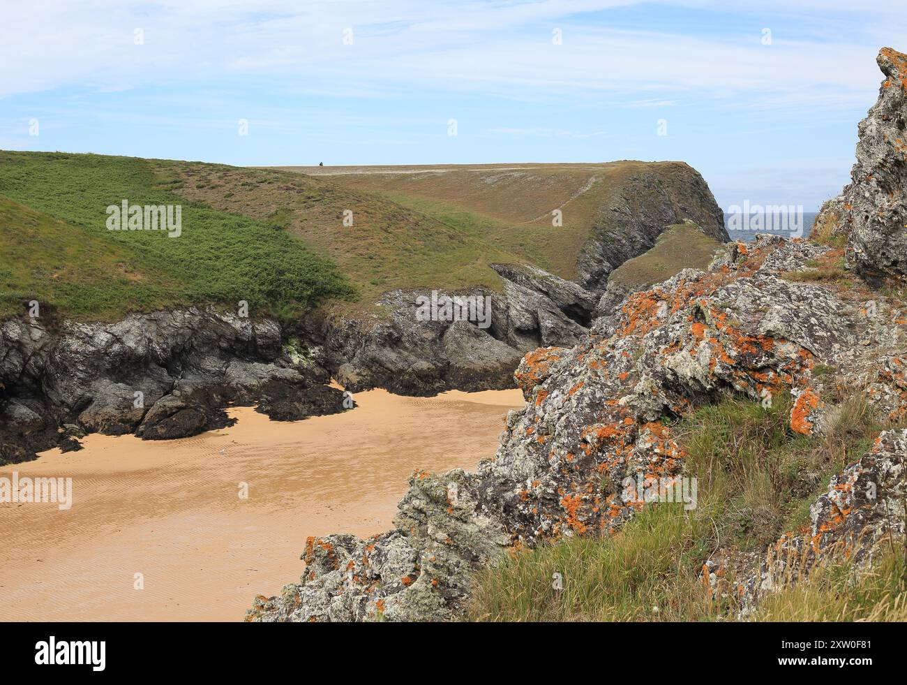 Lichen covered rock with rocky cove and sandy beach at Plage de Vazen ...