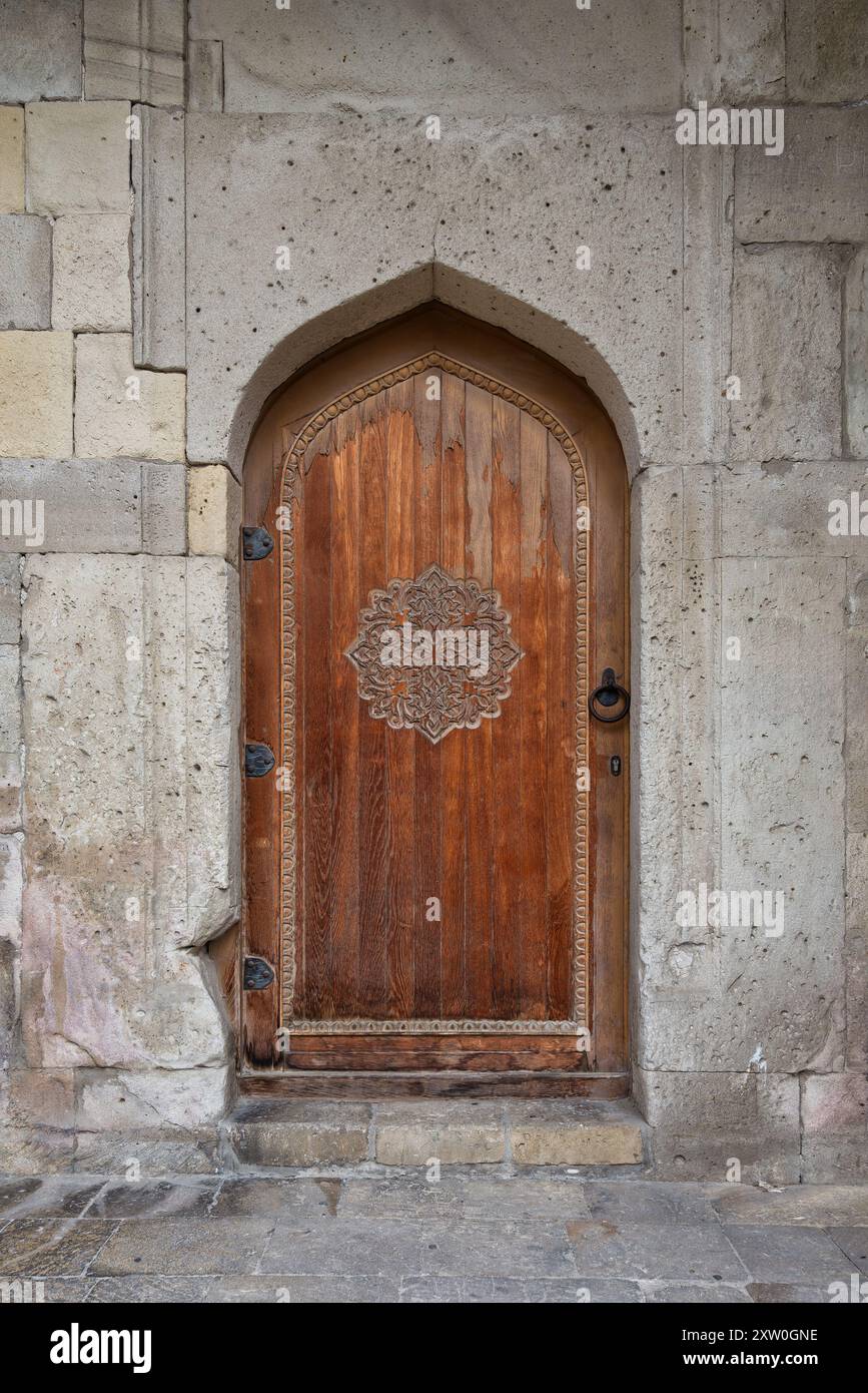 A beautifully detailed arched wooden door features ornate carvings, set ...