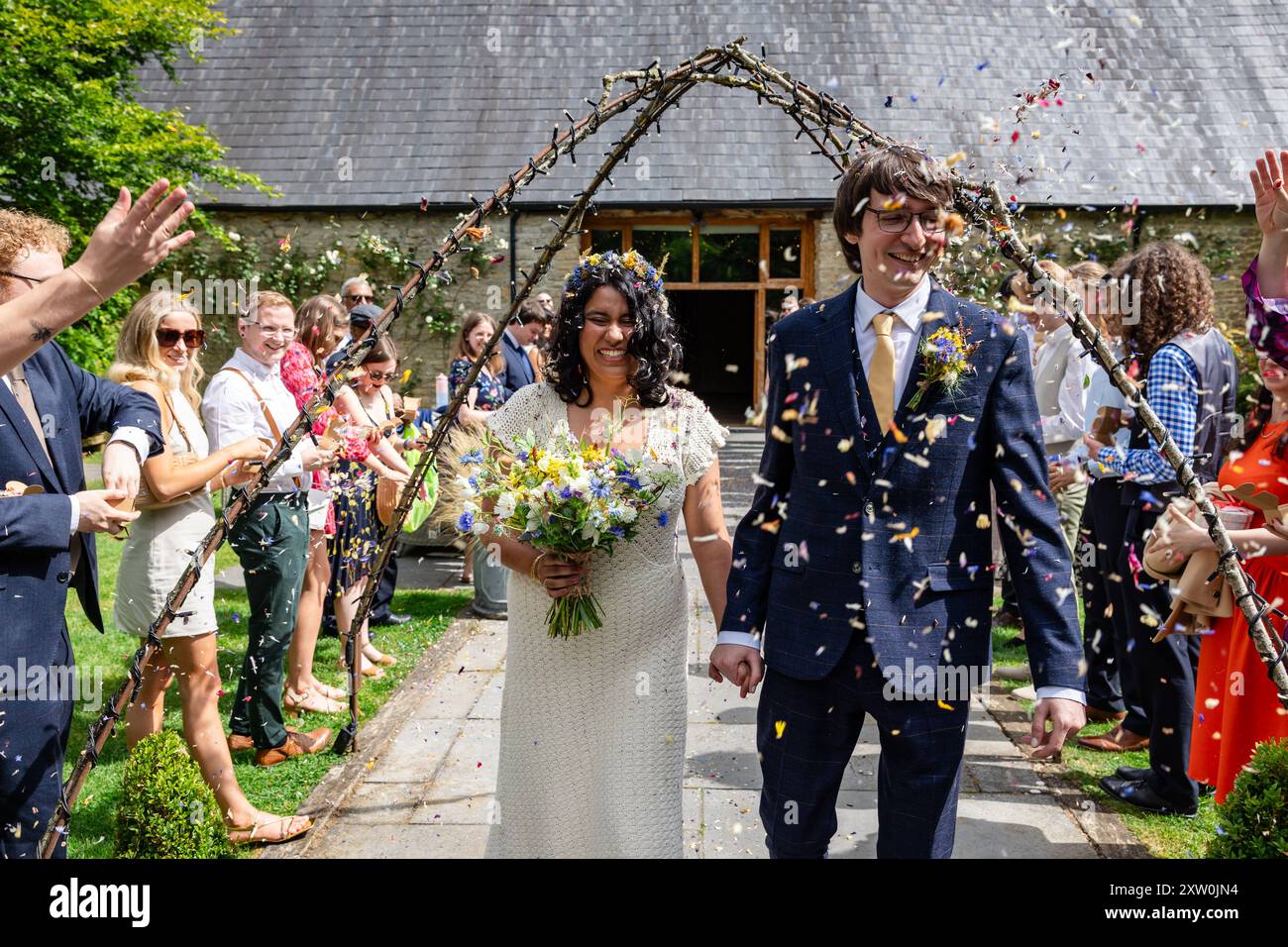 Bride and groom are walking from the wedding ceremony with guests ...