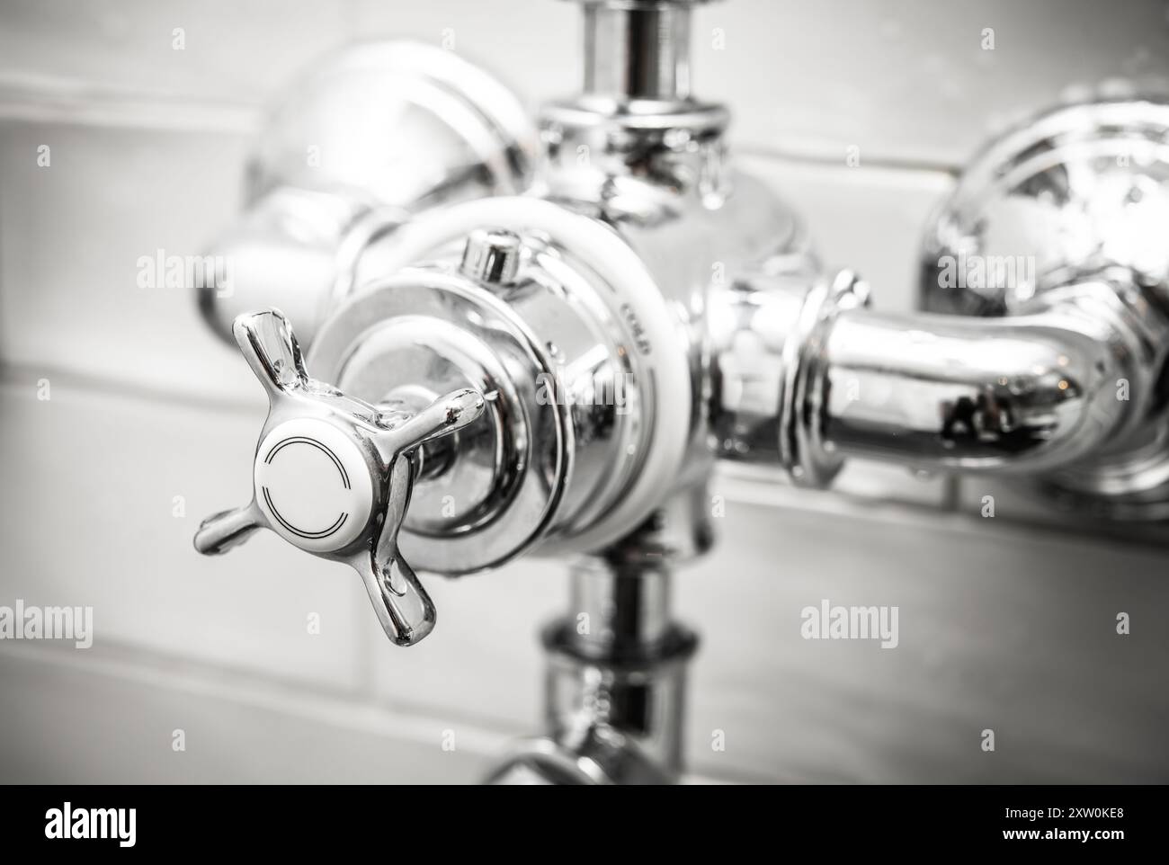 A close-up view of a chrome faucet handle with intricate details ...