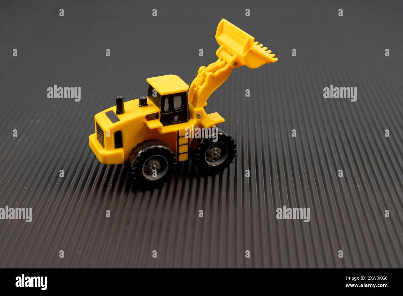 Yellow toy loader with bucket on black background. Development concept ...