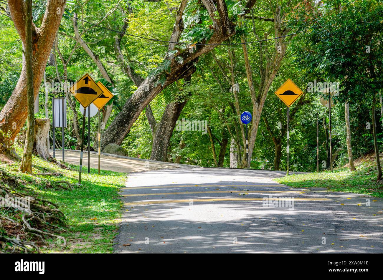 Signs warn of speed bumps on a road in The Penang Municipal Park or ...