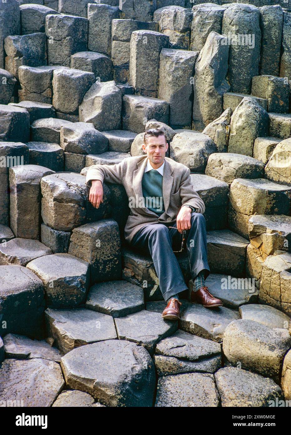 Man sitting on basalt columns rocks at Giant's Causeway, County Antrim ...