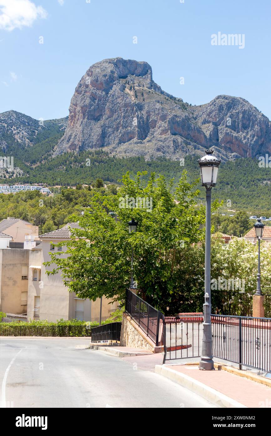 A quiet street in a village with a view of a towering rocky mountain in ...