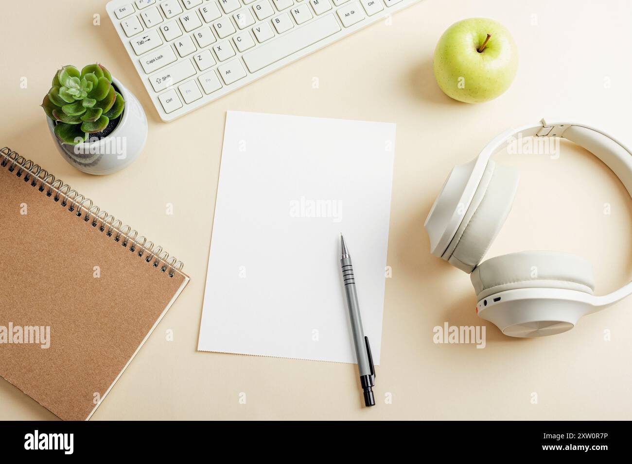 Blank sheet of paper, headphones, keyboard, notepad, pen and apple on ...