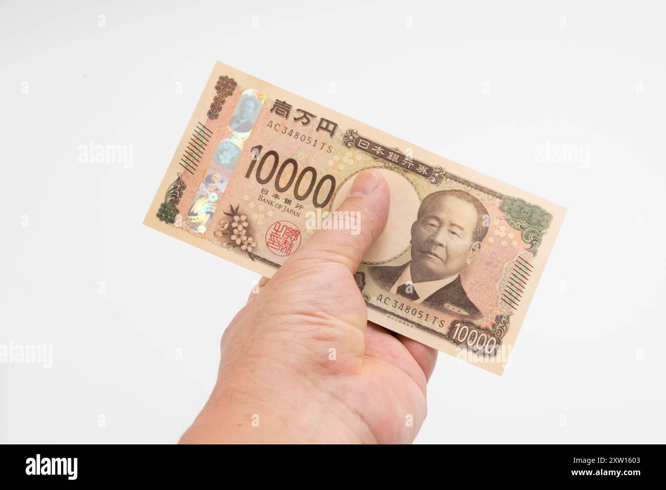 Man's hand holding new Japan 10,000 yen banknote isolated on white ...