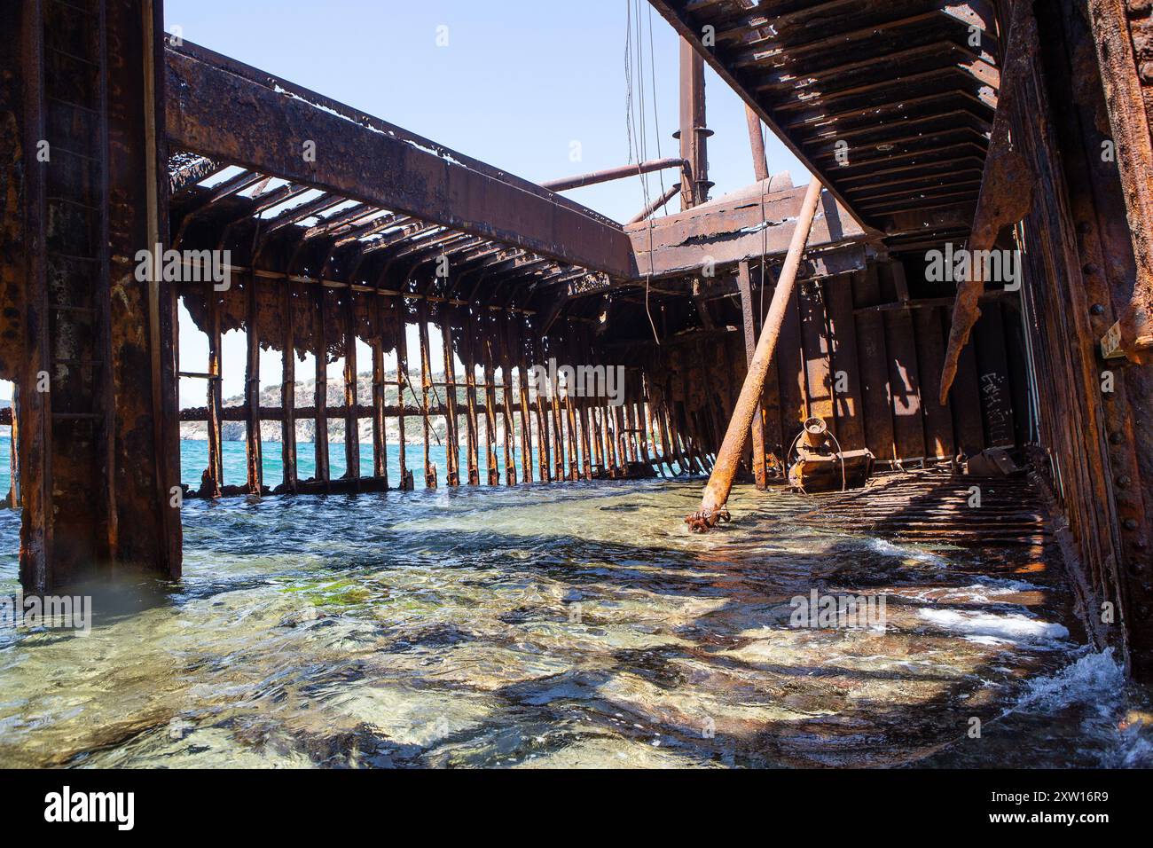 Rusty metal beams of a large shipwreck are deteriorating in ocean water ...