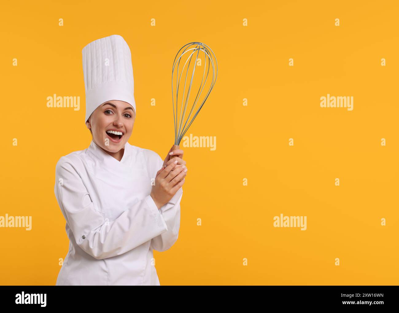 Happy pastry chef with big whisk on orange background. Space for text ...