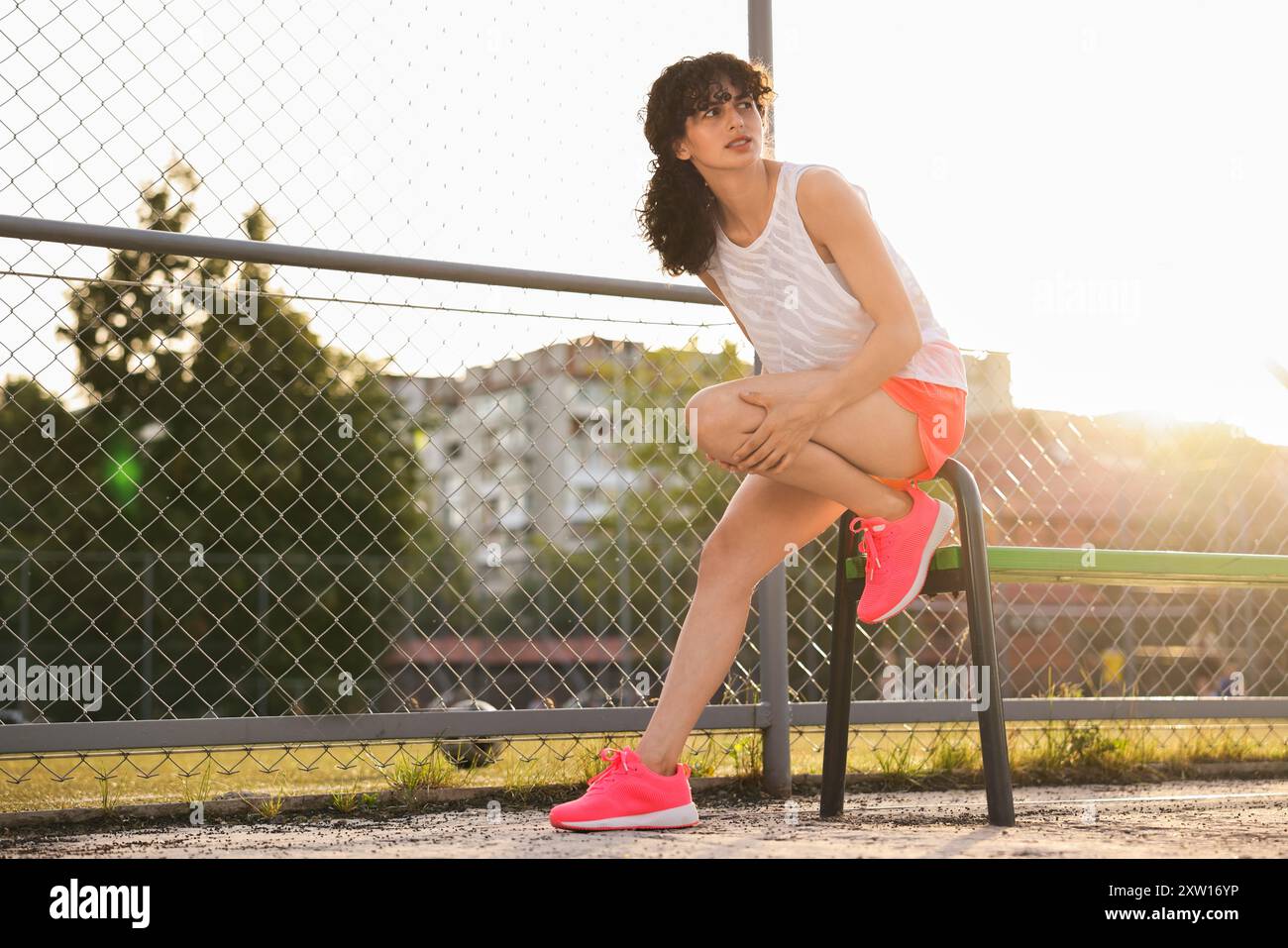 Sportswoman with leg injury suffering from knee pain near bench at ...