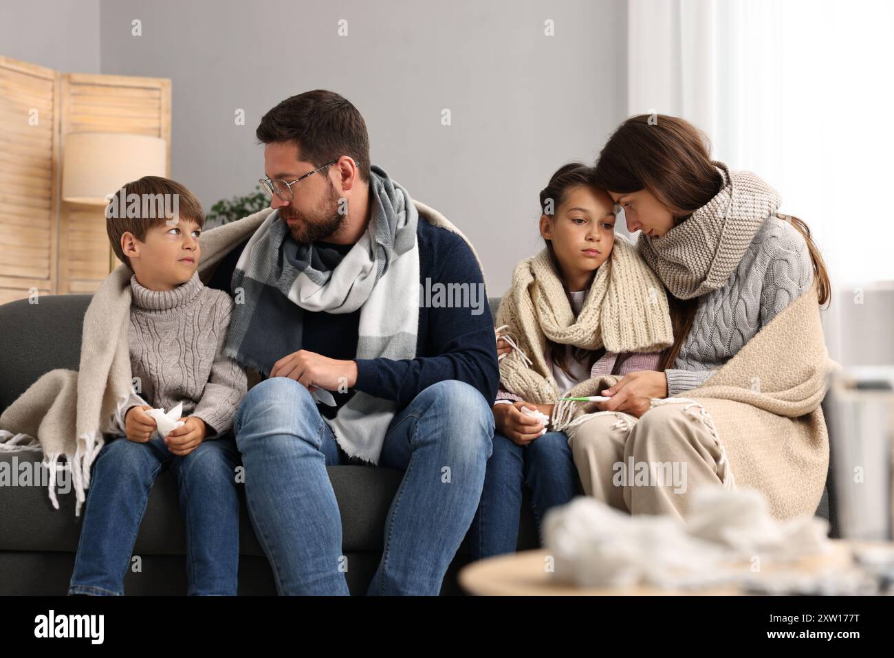 Cold symptom. Family suffering from fever on sofa at home Stock Photo ...