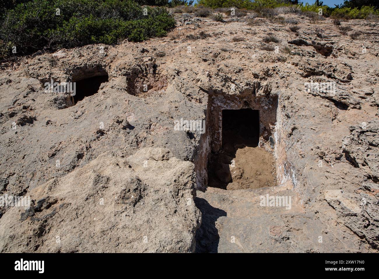 Three ancient greek tombs carved into the side of a hill are open ...