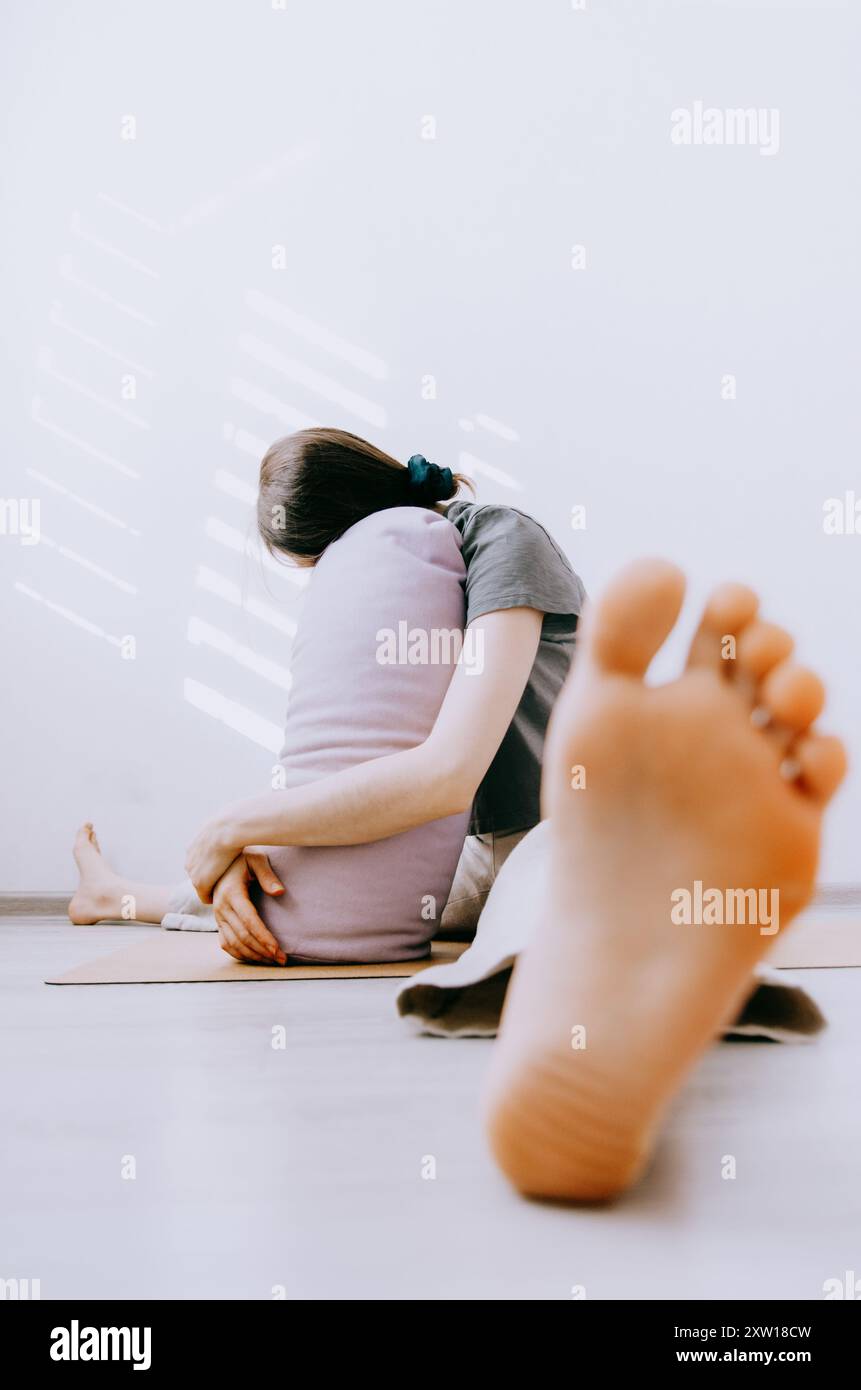 Woman in casual clothing practicing yin yoga wide leg forward fold pose ...