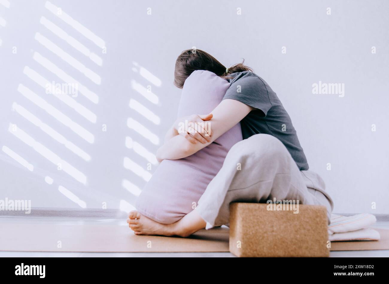 Woman in casual clothing practicing yin yoga wide leg forward fold pose ...