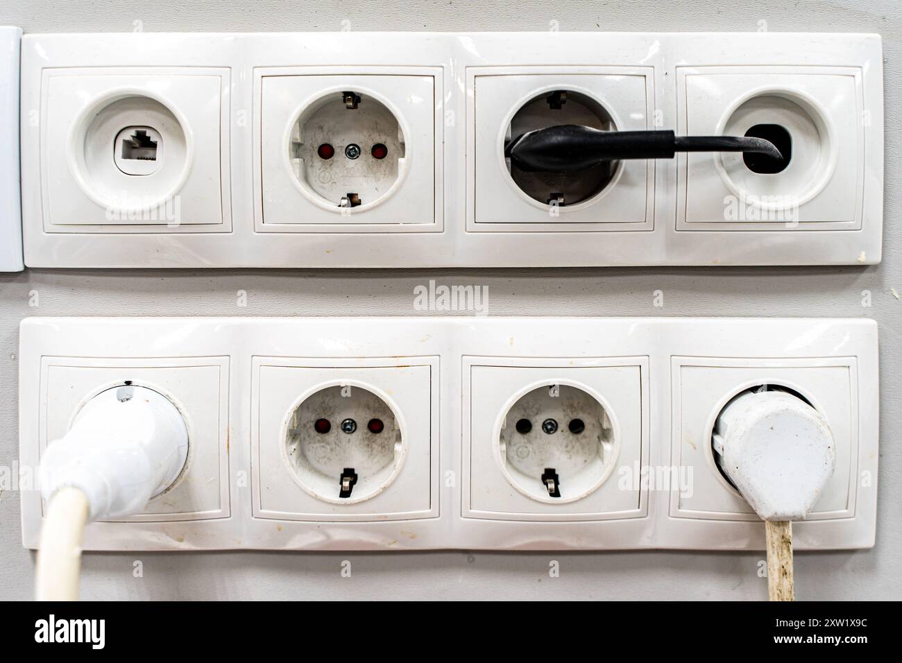 Electrical outlets on a white wall. Electrical cord plugged into a ...