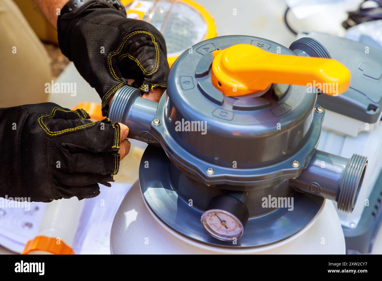 Pool maintenance worker assembles sand filter system tank equipment for ...