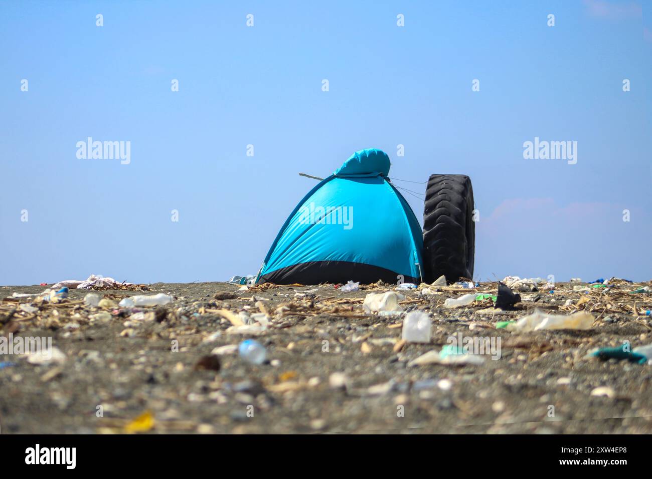Blue tent on the beach. Camping on the shore of the sea. Garbage strewn ...