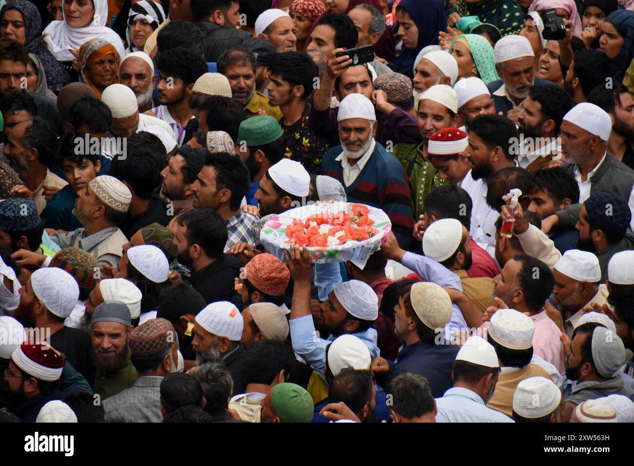 A Kashmiri man, carrying a basket of flowers, makes his way towards the ...