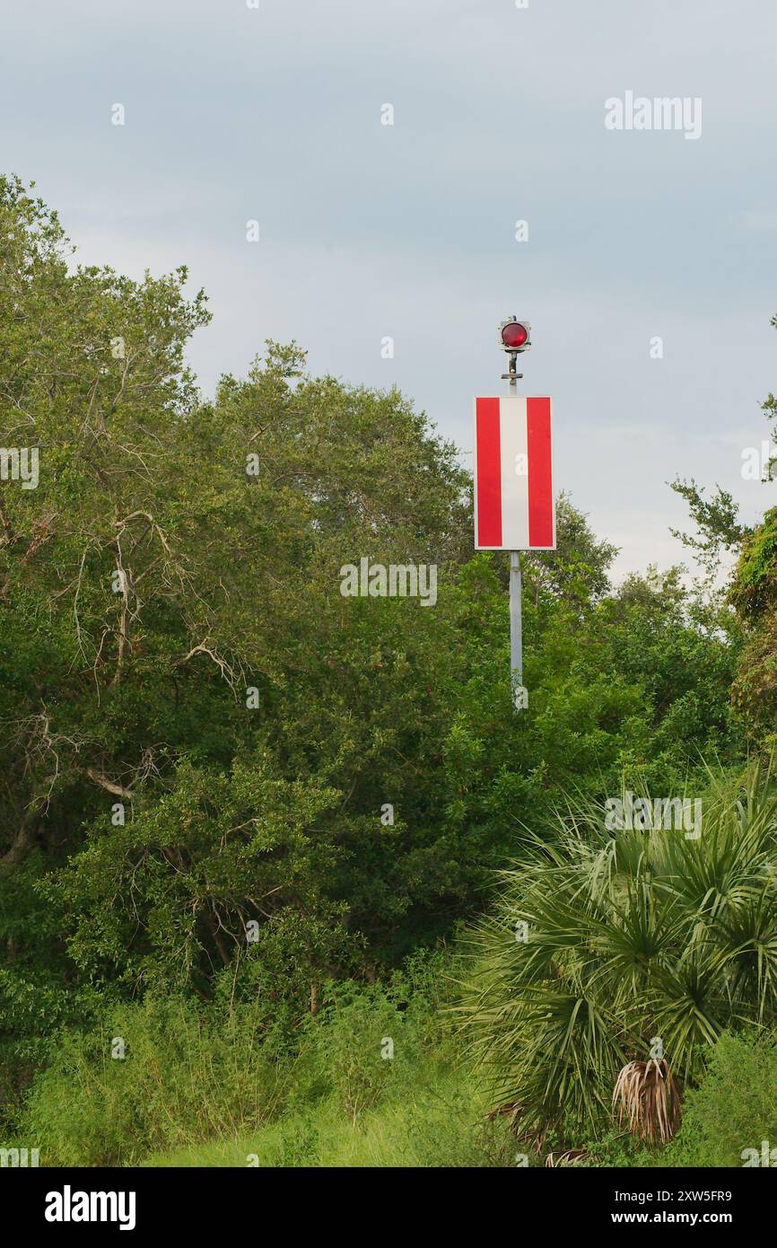 Red and White water navigation sign high in green trees with beacon ...