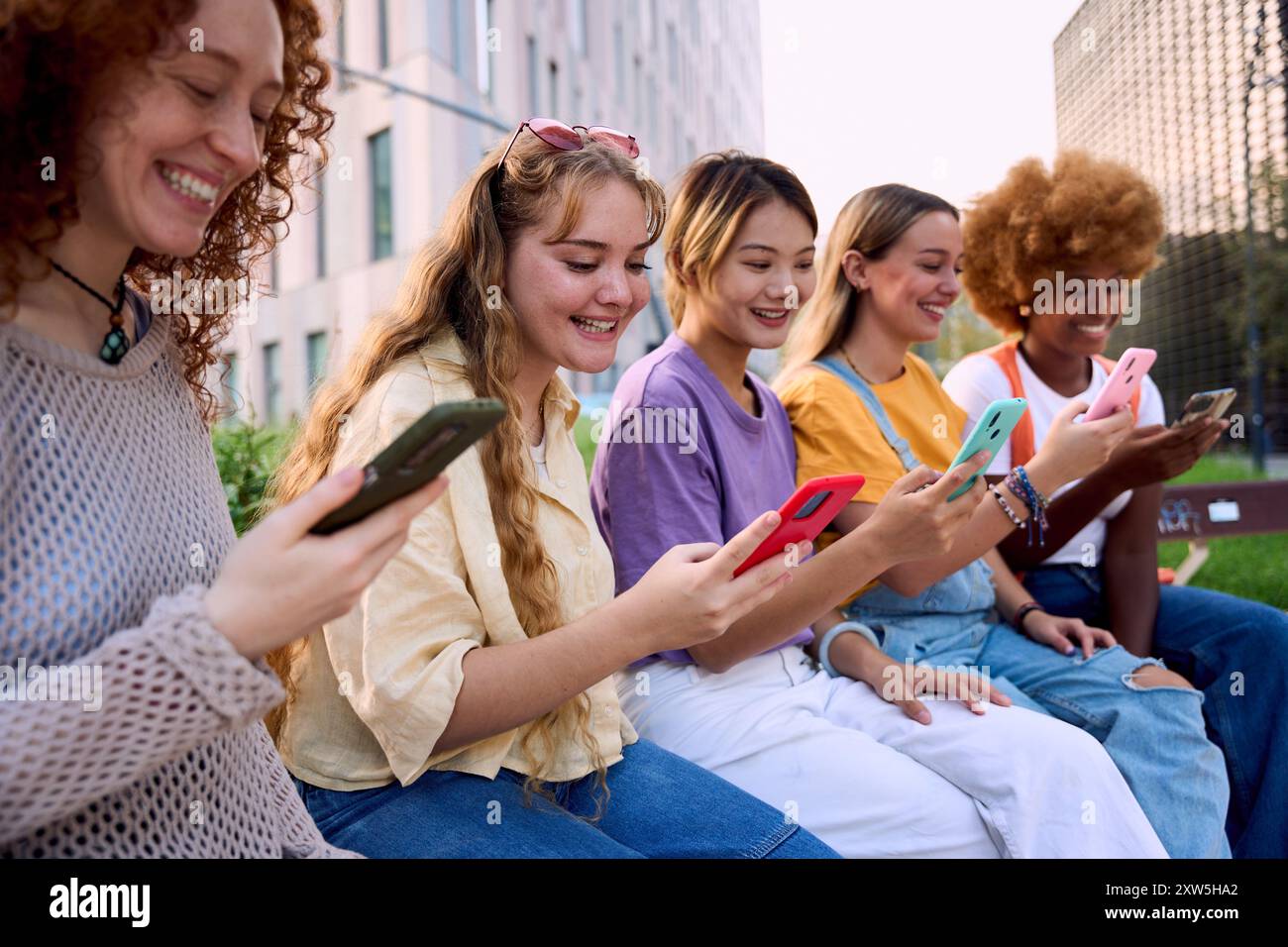 Group of young women using a mobile cell while having fun in the park ...