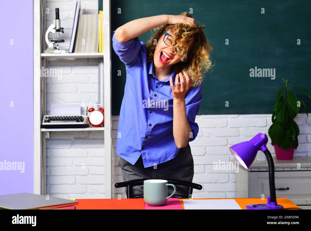 Angry teacher standing at desk in classroom. Hard schoolwork. Stressed ...
