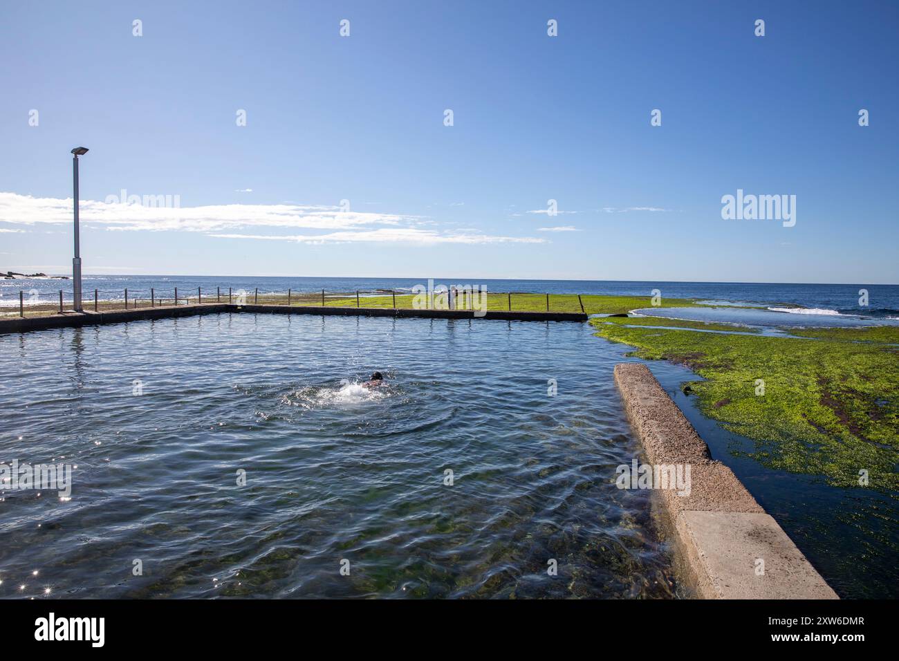 Mona Vale beach ocean rockpool on a winters day with green algae around ...