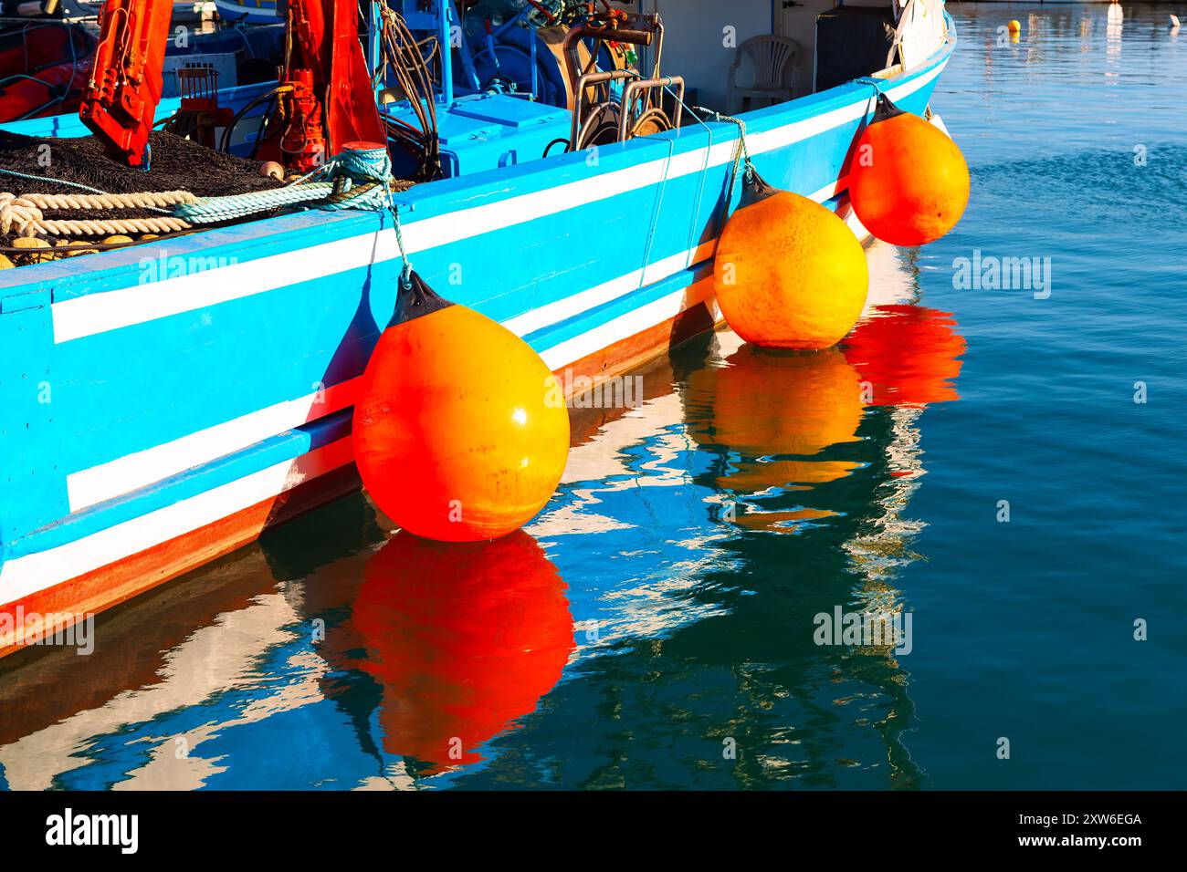 Boat equipped with bright orange buoys, floating calmly on the water ...