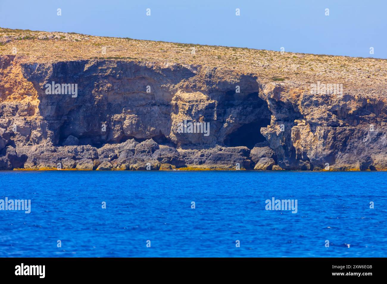 Coastal cave and jagged rocks at seaside. Rocky cliff overlooks ...