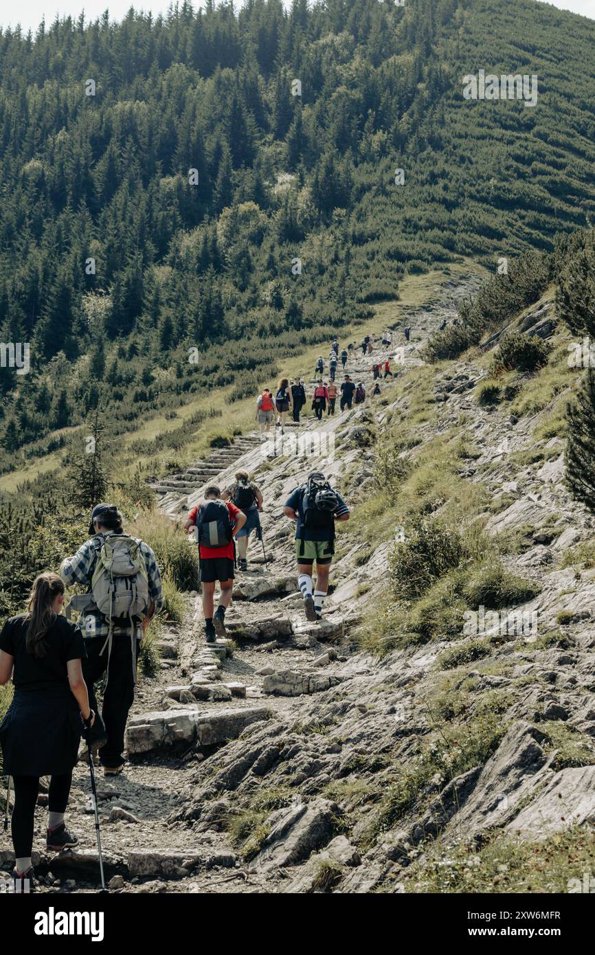 A line of people with hikers on a mountain path going up Stock Photo ...