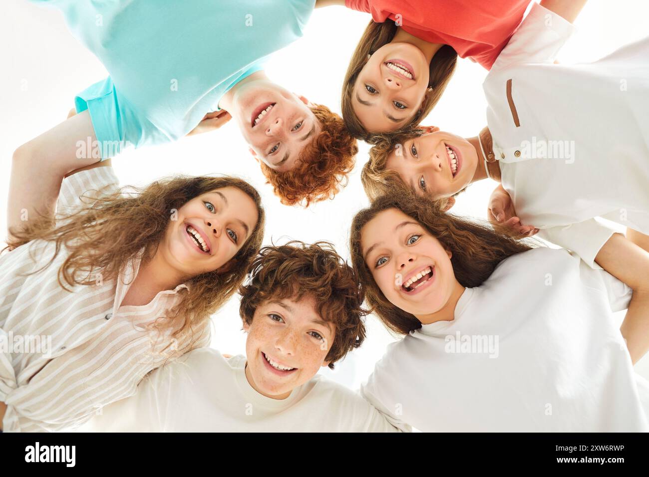 Bottom view of group of preteen friends standing in circle, hugging and ...