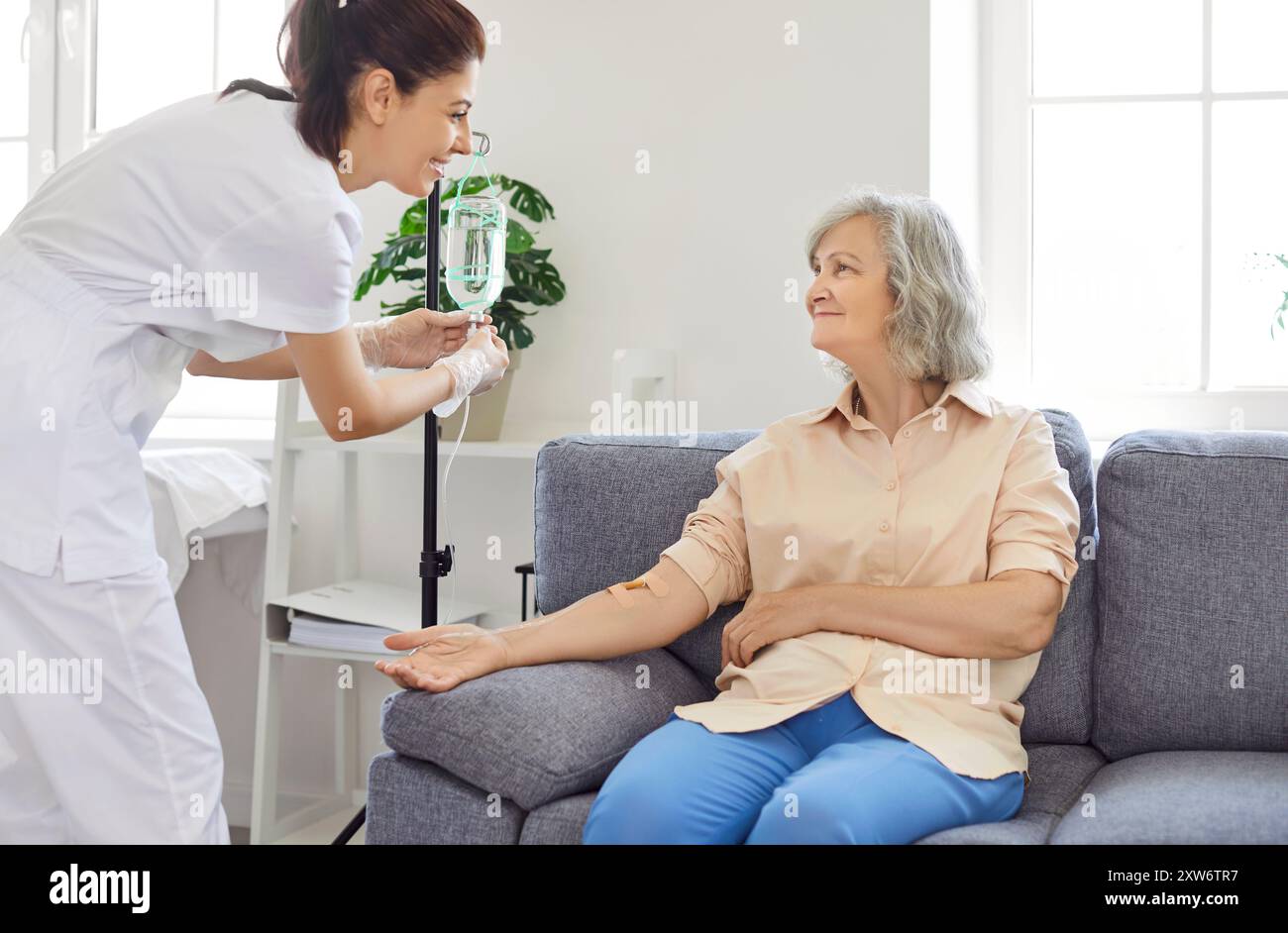 Senior woman with intravenous drip sitting on couch, physician, nurse ...
