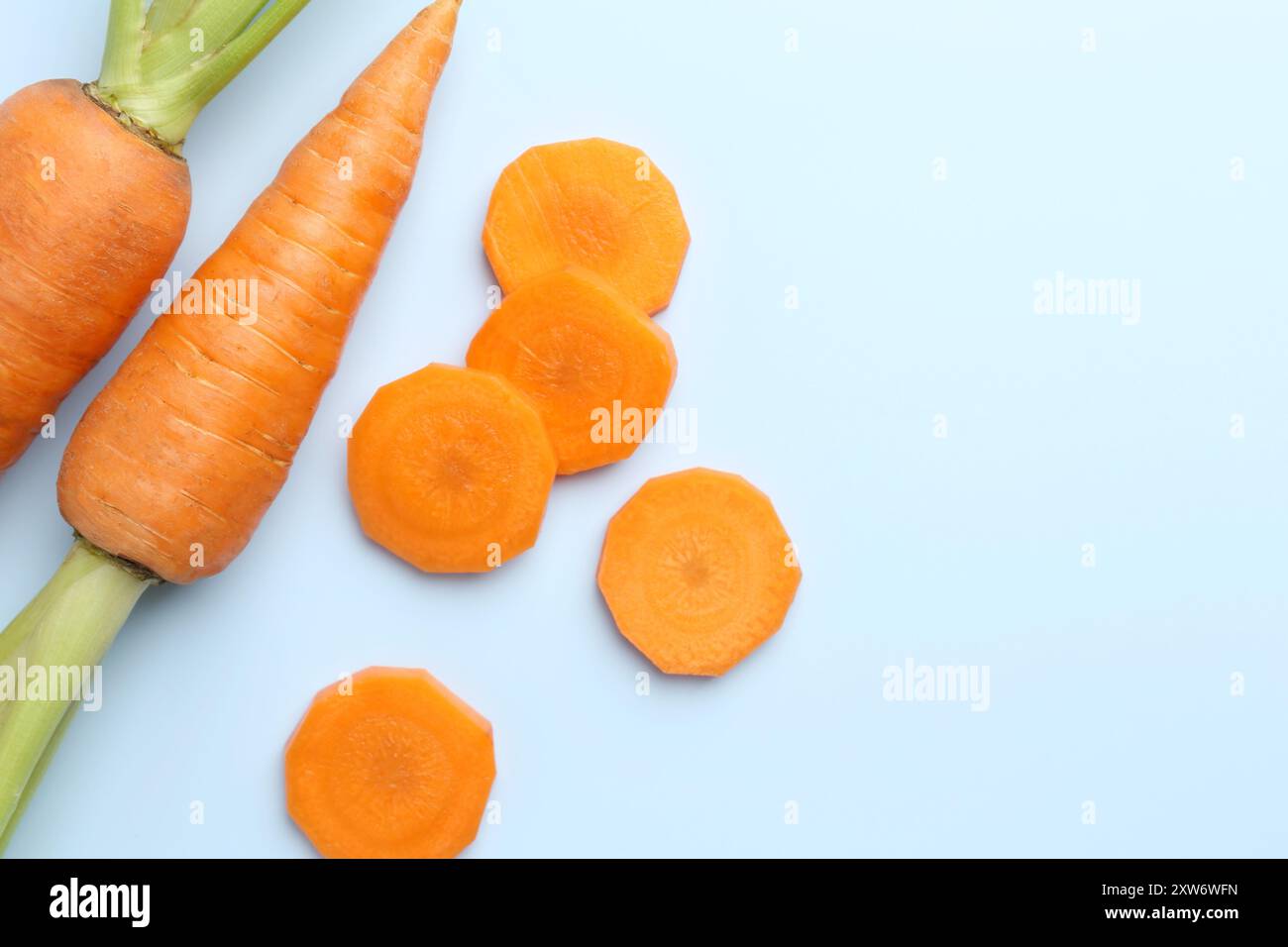 Whole and cut fresh carrots on light background, flat lay. Space for ...